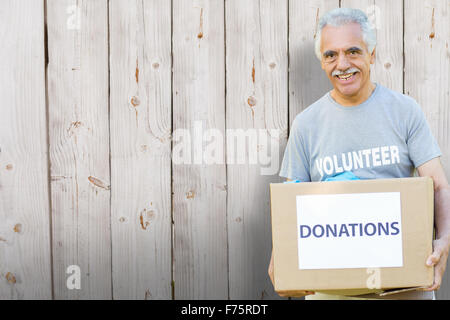 Senior man volunteer holding donations box putting food into a box ...