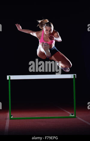 Determined young woman athlete jumping over a hurdles Stock Photo - Alamy
