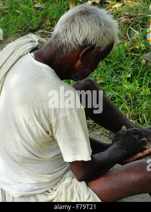 An old poor man from India on the streetside walking with his stick ...