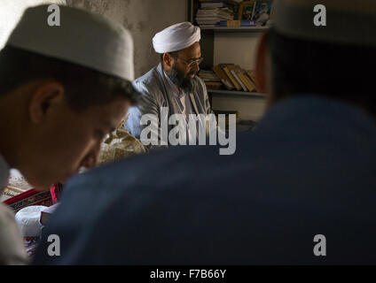 Shia Muslim mullah in turban and gown seated at prayer in the Masjed-e ...