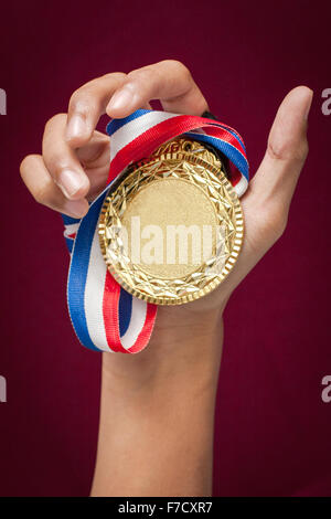 Hand holding gold medal isolated on white background. The winner and ...