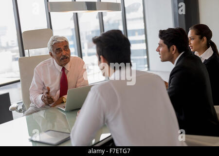 India, Senior businessman leading discussion with three colleagues ...