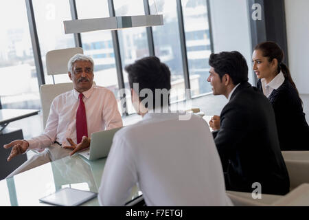 India, Senior businessman leading discussion with three young ...