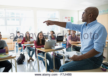 High school teacher calling on students with hands raised during lesson ...