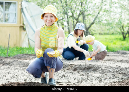 Happy family sows seeds in soil at field Stock Photo - Alamy