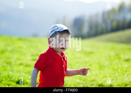 Running baby boy in mountains on grass background Stock Photo - Alamy