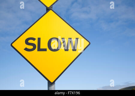 Yellow Slow Sign against Blue Sky Background Stock Photo - Alamy