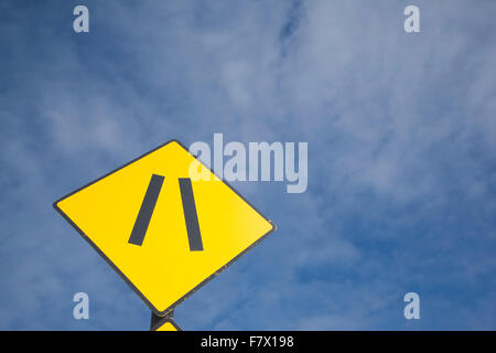 Road Narrowing Sign against Blue Sky Background Stock Photo - Alamy