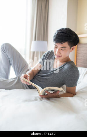 Young Chinese man reading a book on the sofa Stock Photo - Alamy