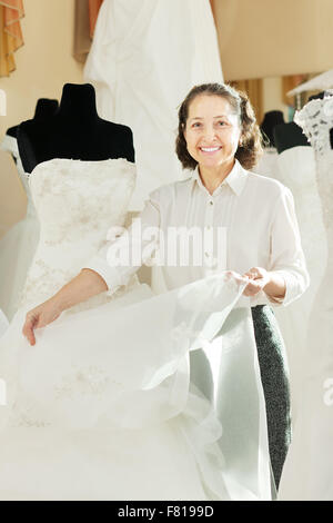 Shop assistant shows bridal dress at wedding store Stock Photo - Alamy