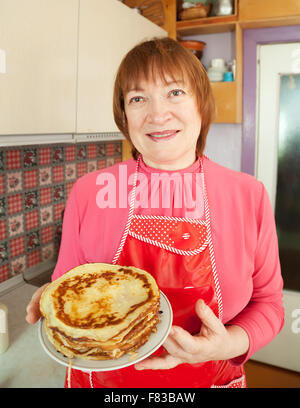 Mature woman with cooked pancakes in kitchen Stock Photo - Alamy