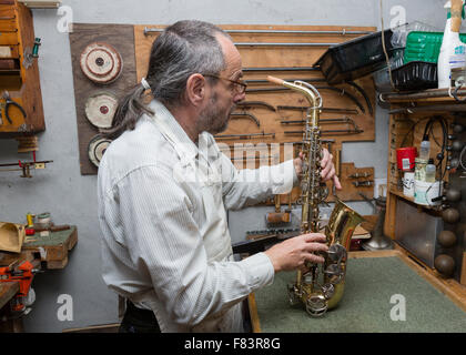 Brass and woodwind musical instrument repair technician, in workshop ...