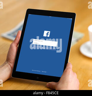 Facebook App login page on iPhone with people using tablet background ...