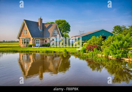 Red bricks house in countryside near the lake with mirror reflection in ...