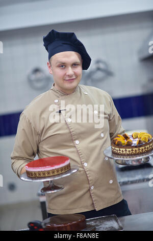 Closeup of a concentrated male pastry chef decorating dessert cake food ...