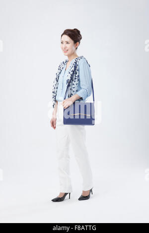 Side view of woman with bag standing on city street during sunny day ...