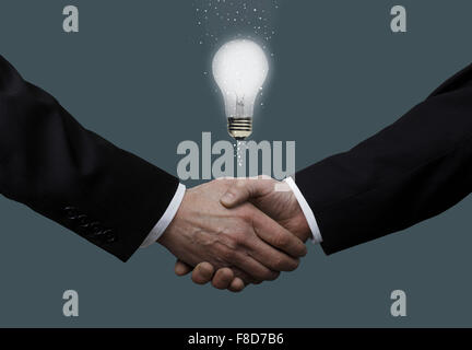 Businessmen Shaking Hands With Light Bulb Stock Photo - Alamy