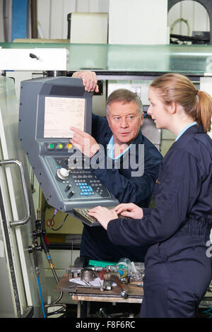 A female cutting machine operator trainee is deburring a component ...