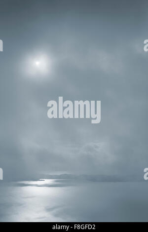 A vertical shot of the sun shining over a rural trail near a seashore ...