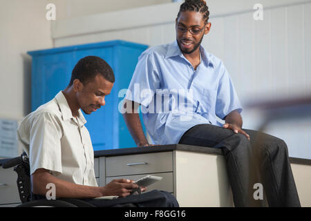 Paraplegic student and classmate using digital tablet Stock Photo - Alamy