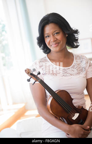 Serene African American female musician playing melody on violin while ...