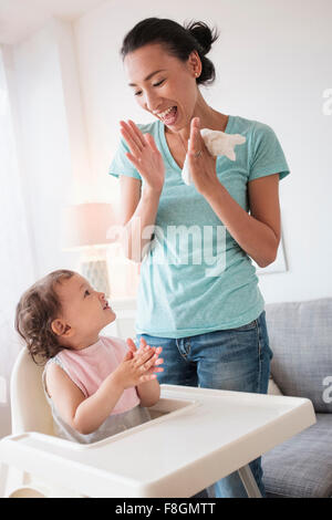 Happy mother and daughter playing clapping game on sofa Stock Photo - Alamy