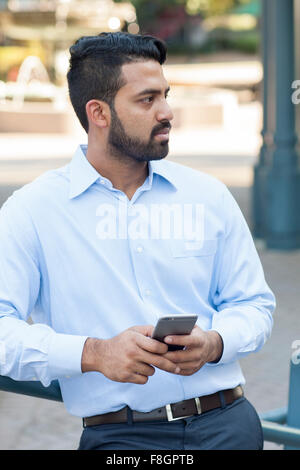 Young brunette indian businessman using cellphone and headphones while ...