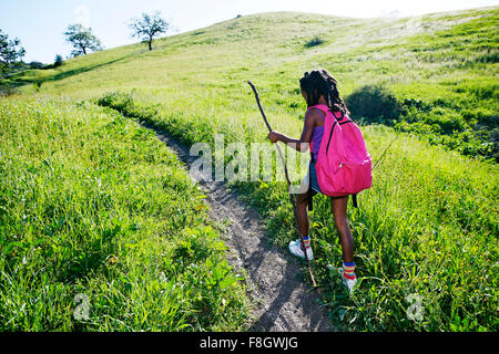 Back view of girl walking on field path, shot with selective focus ...