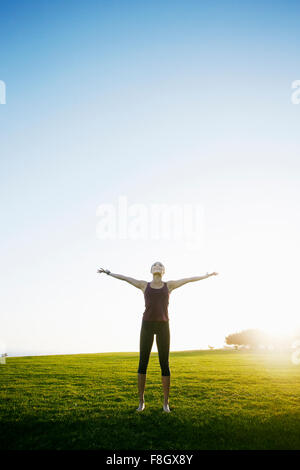 Woman with arms outstretched standing on wheat field in front of sky ...