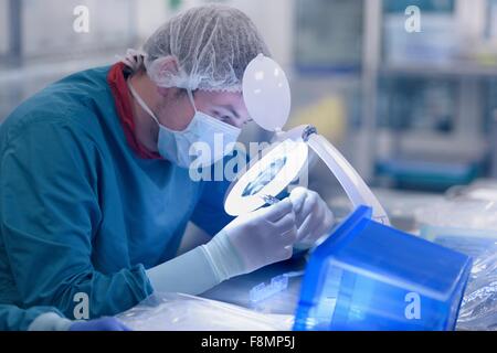 Worker inspecting surgical instruments in clean room of surgical ...