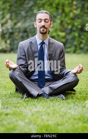 Young businessman meditating in the garden Stock Photo - Alamy