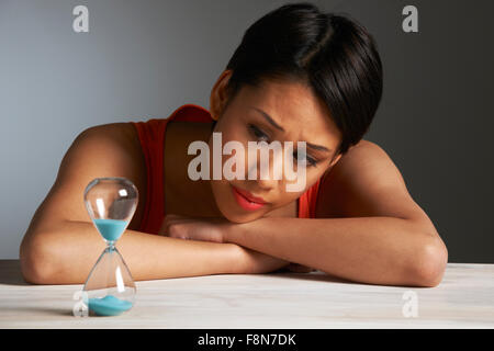 Sad Woman Looking At Hourglass Stock Photo - Alamy
