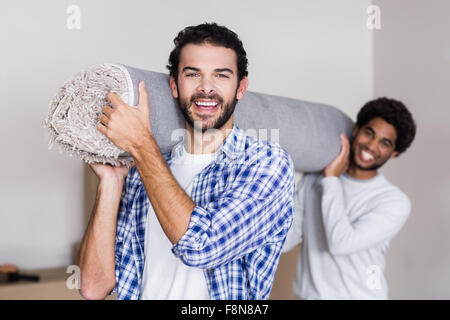 Young man holding rolled carpet against white background Stock Photo ...