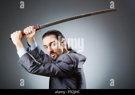 Angry businessman with sword in dark room Stock Photo - Alamy