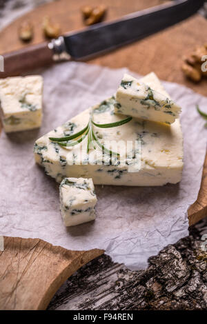 A slice of mature Stilton cheese on a plate with round whole wheat ...