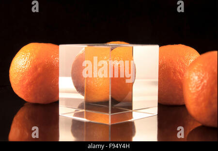 Tangerines with a glass cube on the black background Stock Photo - Alamy