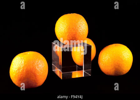 Tangerines with a glass cube on the black background Stock Photo - Alamy