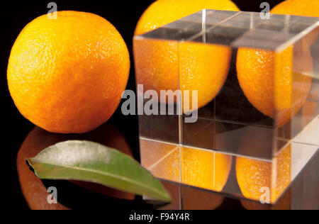 Four tangerines with a glass cube Stock Photo - Alamy