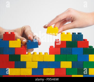 two hands teamwork stack up lego set as a wall on white background ...