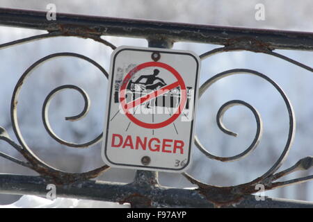 Sign posted on retaining wall warning of danger of climbing railing ...
