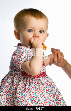 Portrait of a caucasian baby girl eating pasta from plate sitting on ...