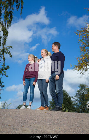 A family hugging each other and looking into the distance outdoors and ...