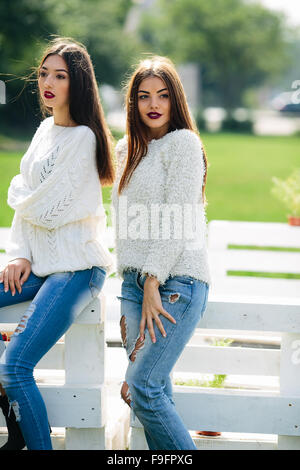 Two girls lean bench Stock Photo - Alamy