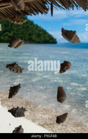 Shells Hanging From Bamboo Roof in front of crystal clear water and ...