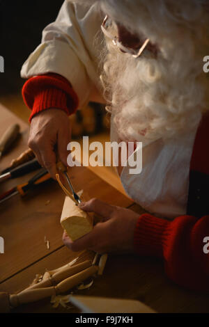 Santa Claus at Home carving something from wooden plank Stock Photo - Alamy