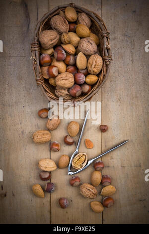 Wickerbasket, walnuts, almonds, hazelnuts and nutcracker on wood Stock ...