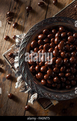Tasty chocolate candies with coffee beans and nuts on wooden background ...