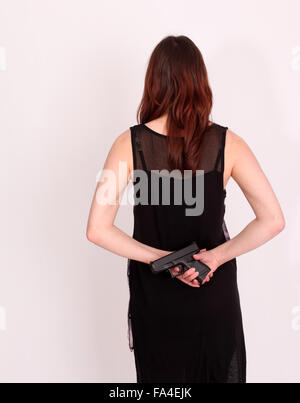 Woman holding a gun behind her back Stock Photo - Alamy