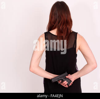 Woman holding a gun behind her back Stock Photo - Alamy