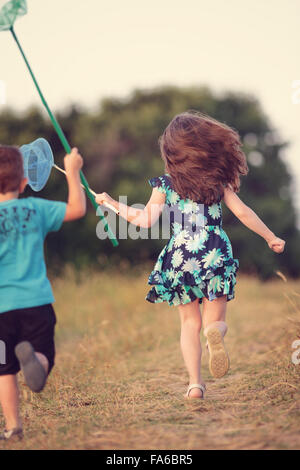 Boy chasing butterfly vertical Stock Photo - Alamy